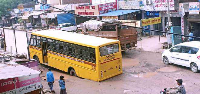 School bus stuck in pothole - The Tribune